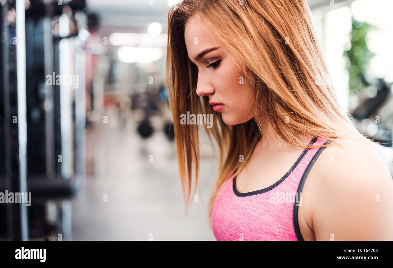 A portrait of beautiful young sad girl or woman in a gym. Copy space ...