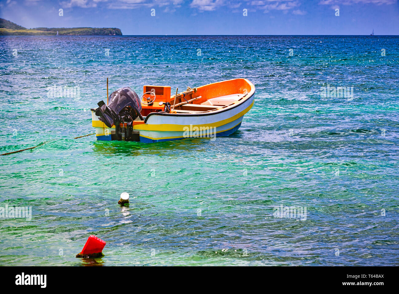 Small wooden colorful boat on crystal blue water ocean at gold time ...
