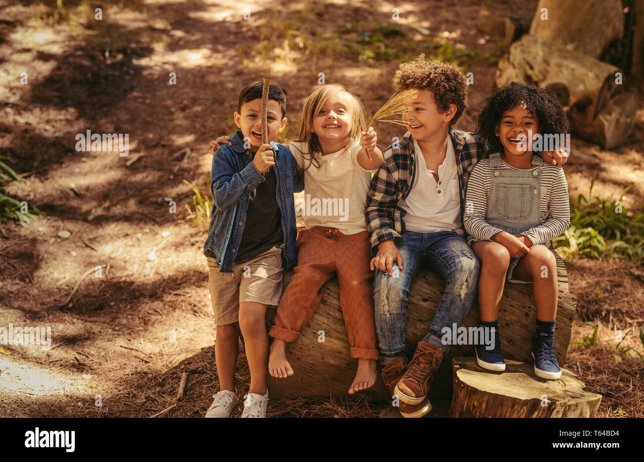 Group of boys and girl sitting on a log. Cute kids outdoor enjoying ...