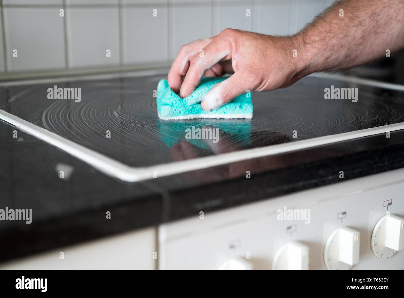 Close up view of a modern house husband cleaning a stove in the kitchen ...