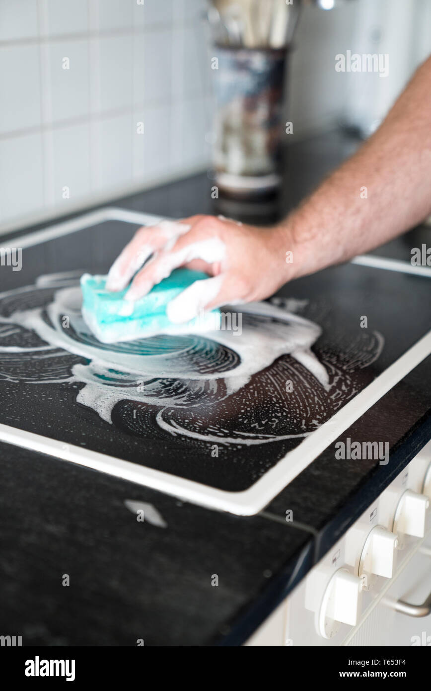 Close up view of a modern house husband cleaning a stove in the kitchen ...
