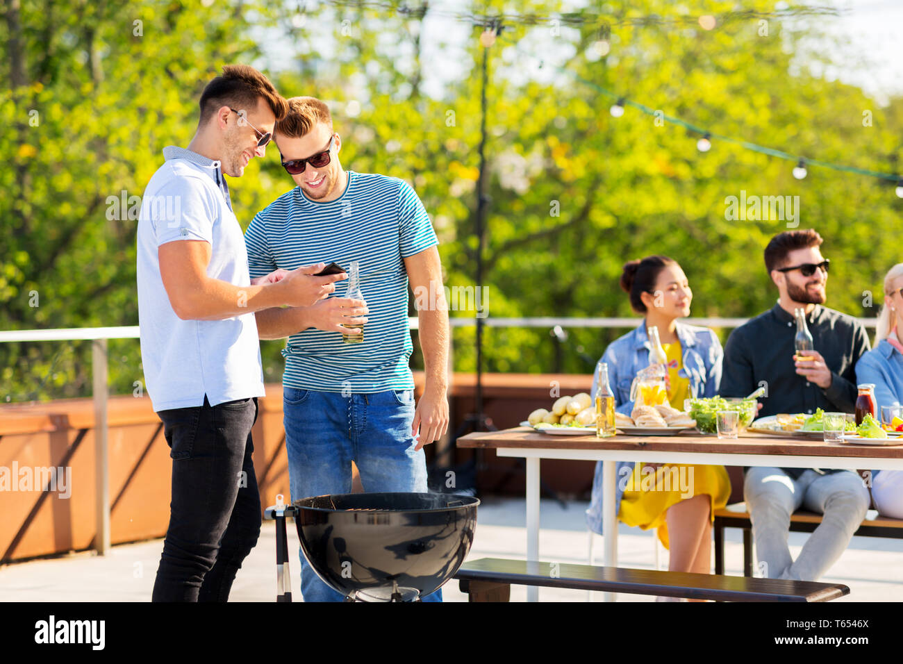 happy friends grilling at bbq party on rooftop Stock Photo - Alamy