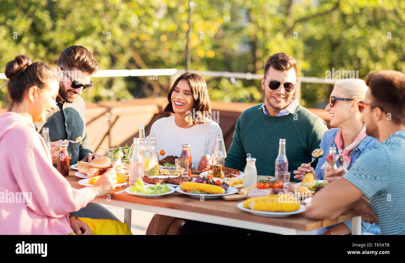 happy friends eating and drinking at rooftop party Stock Photo - Alamy