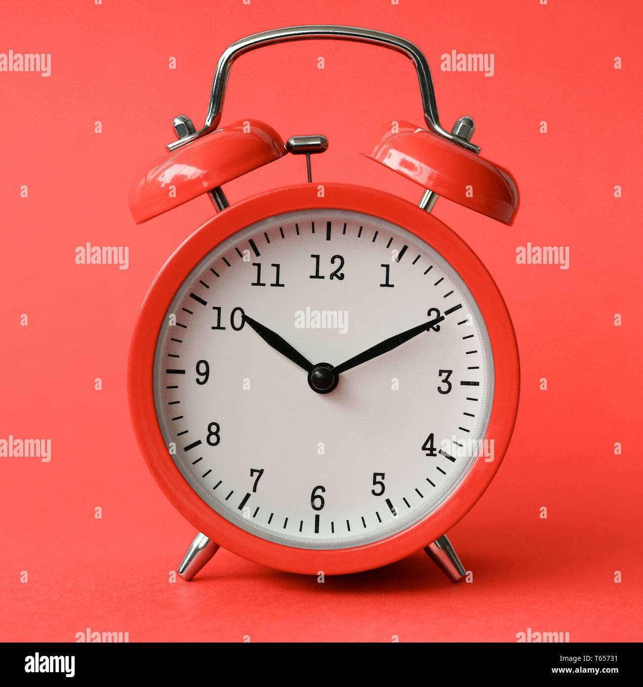 Coral old alarm clock on red background Stock Photo - Alamy