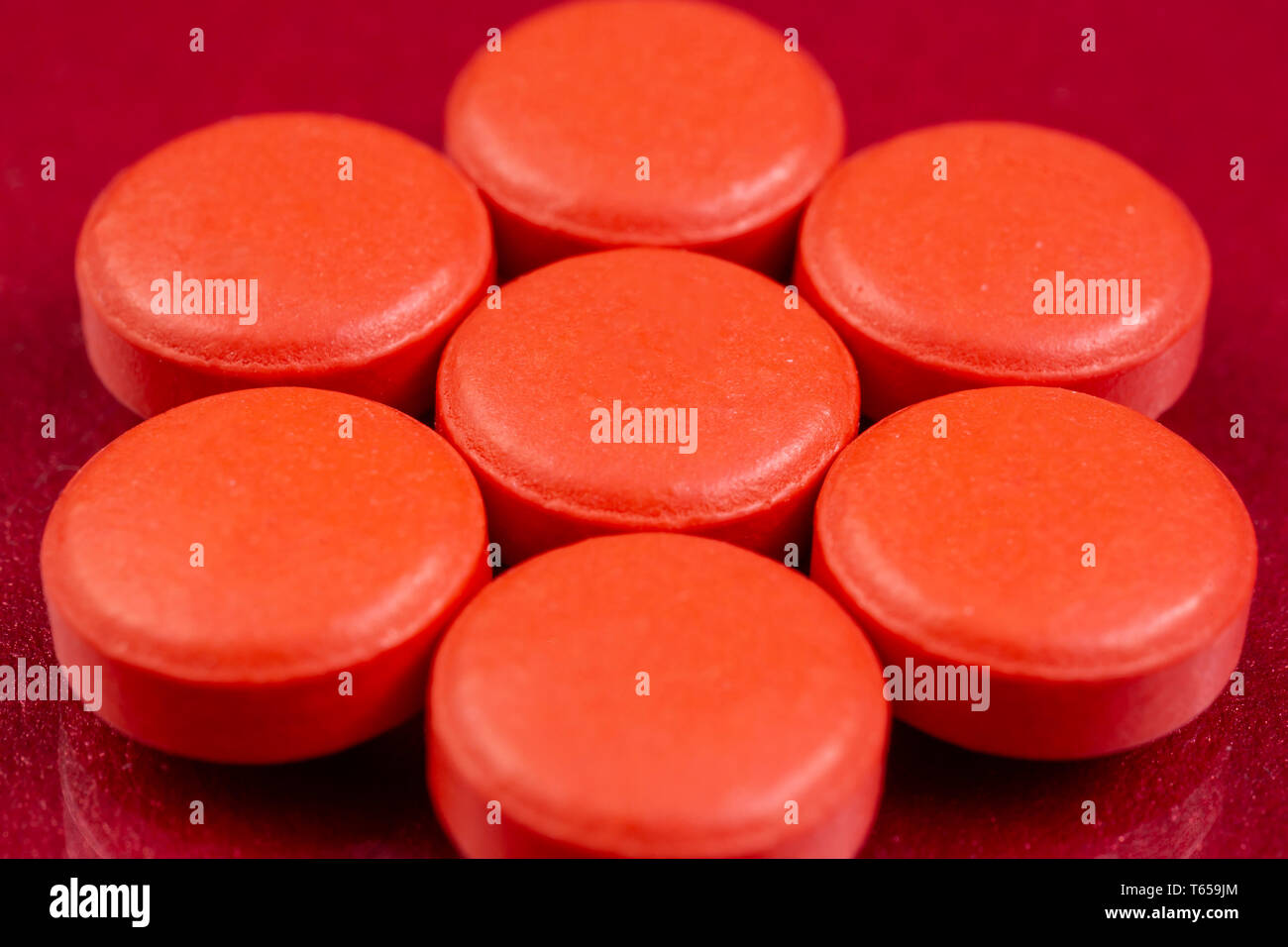 Red pills isolated on a red reflective background. Global ...