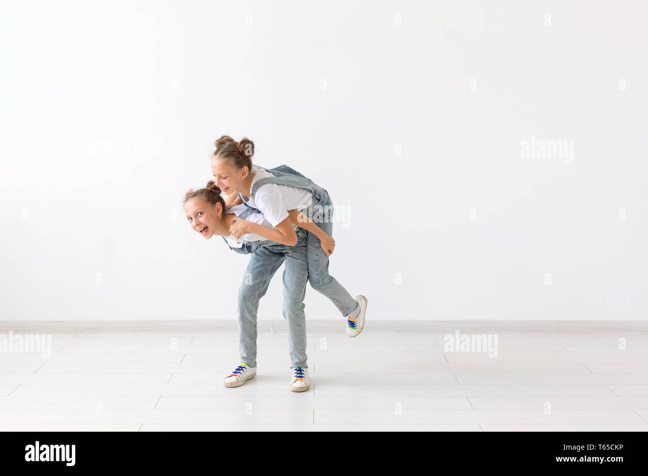 Family and love concept - happy twin girl giving piggyback ride to her ...