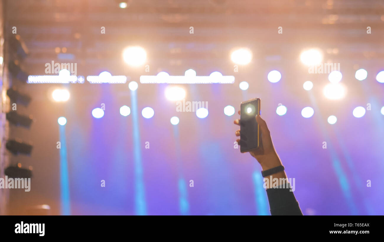 Man hand silhouette holding smartphone with flashlight on live music ...