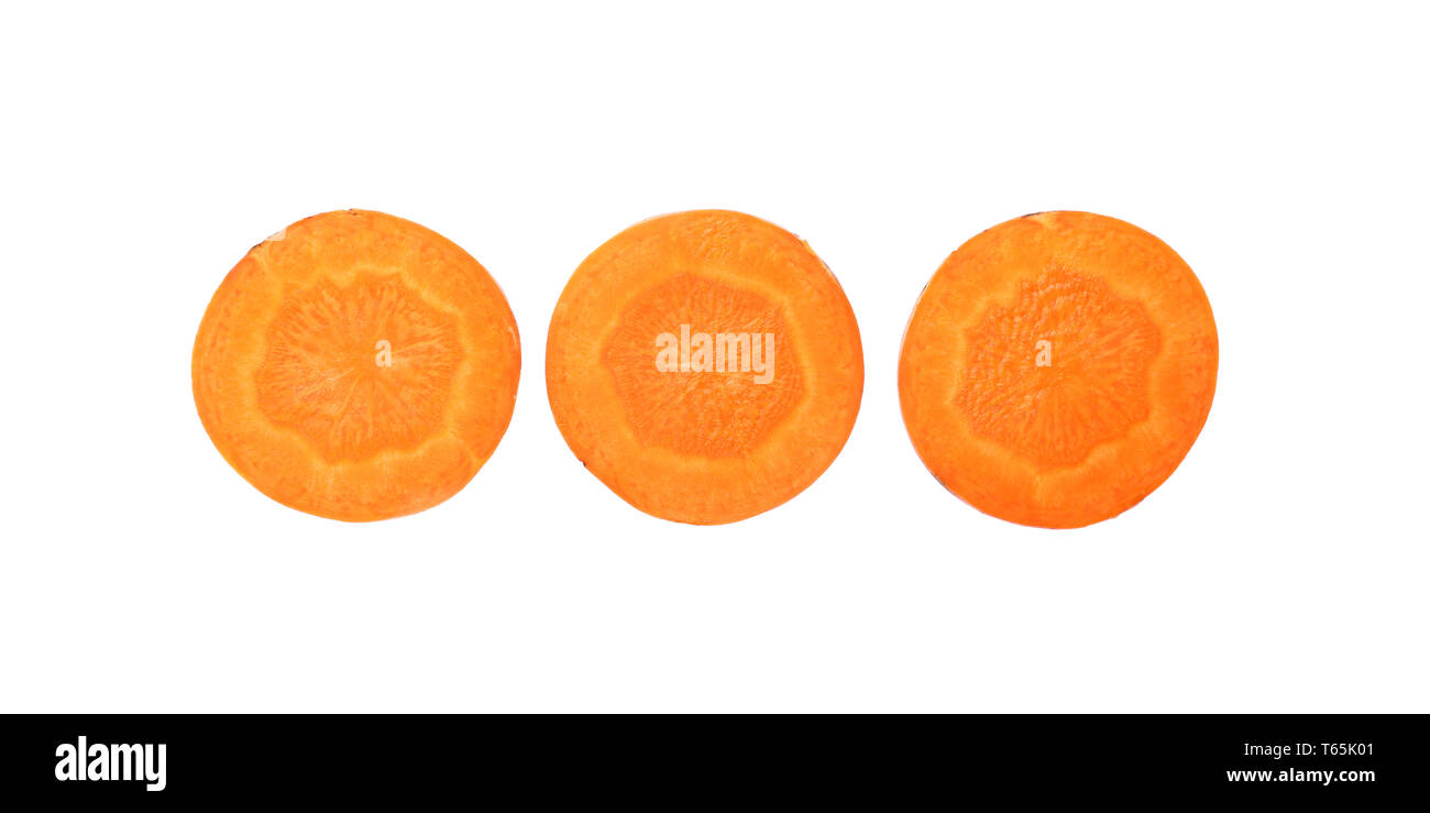 Close up three round thin cut slices of fresh carrot, backlit and ...