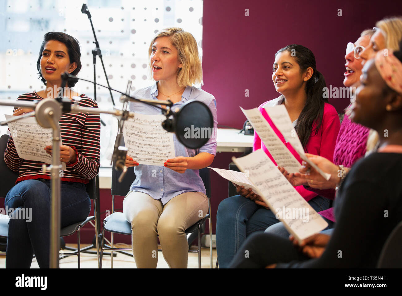 Womens choir with sheet music singing in music recording studio Stock ...