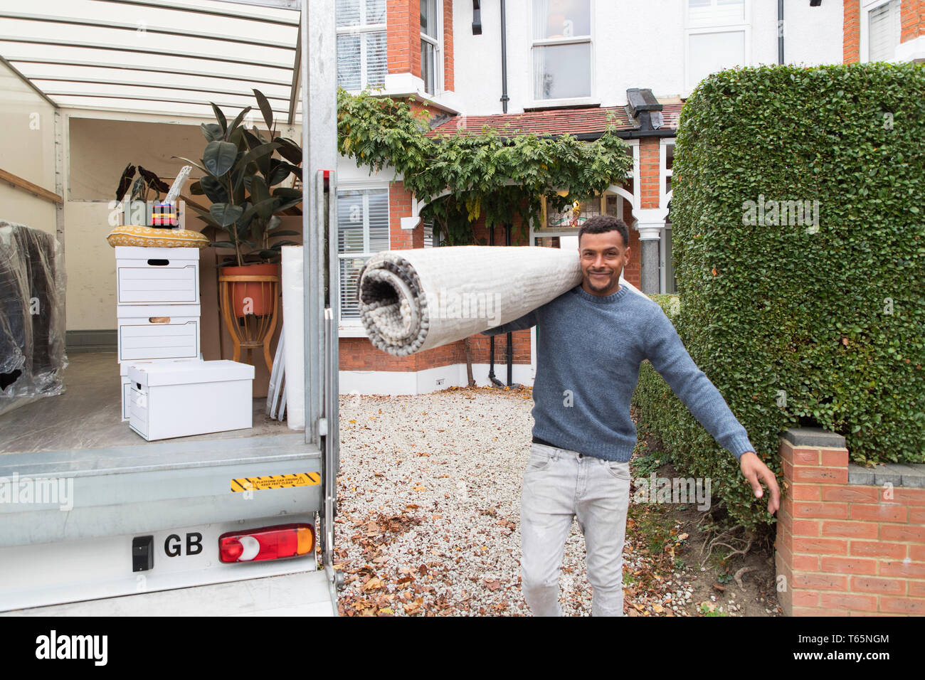 Portrait confident man carrying rug outside moving van, moving house ...