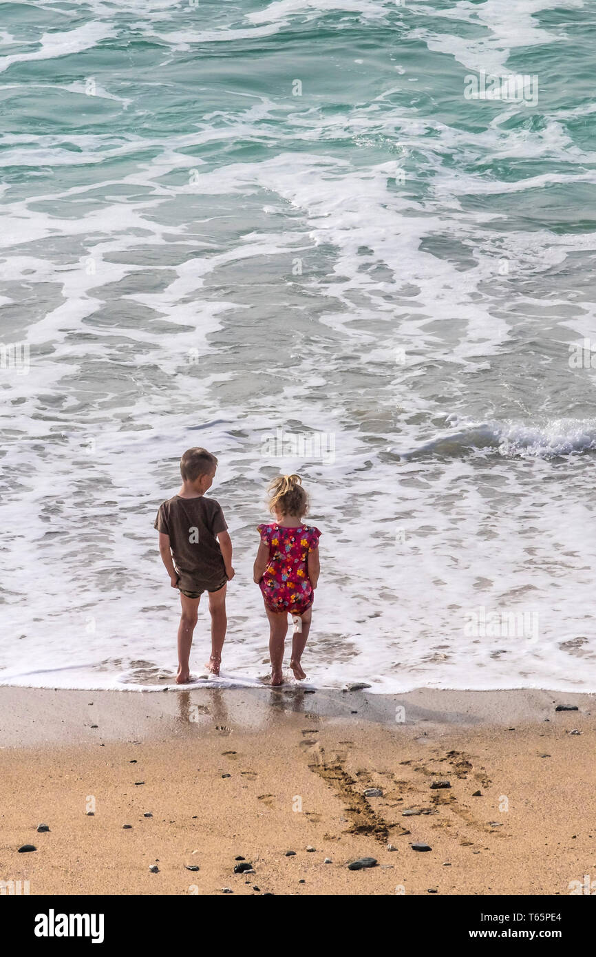 Two young children paddling in the sea at Fistral Beach in Newquay in ...