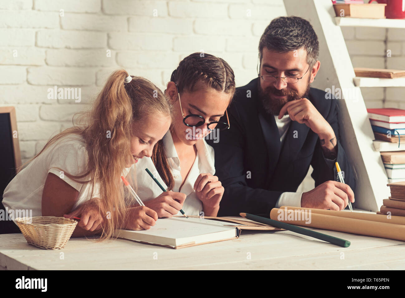 father and daughters writing white home schooling. Father helps ...