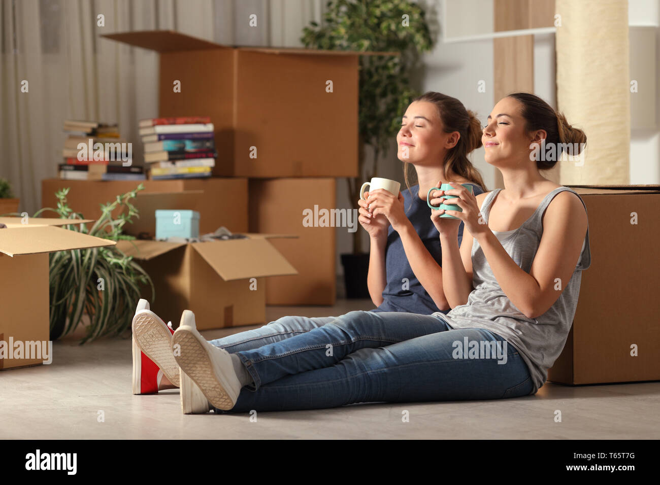 Two happy roommates moving home resting breathing fresh air sitting on ...