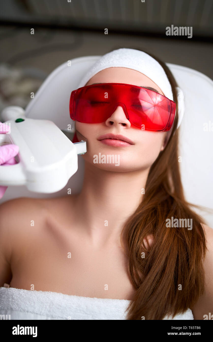 Beautician doctor doing laser RF rejuvenation for attractive young ...