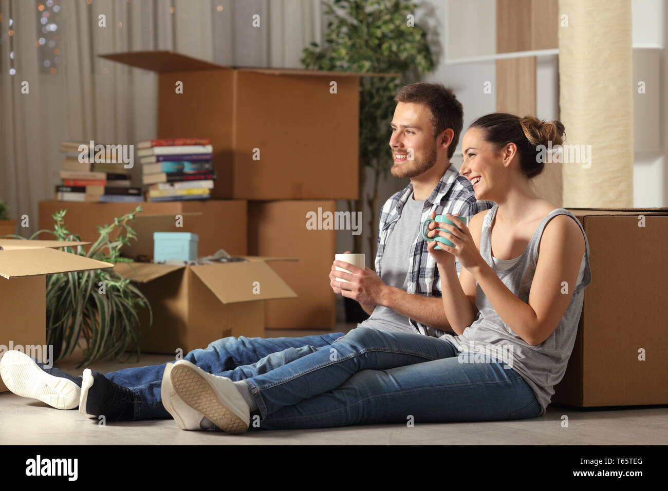 Happy couple moving home resting sitting on the floor contemplating ...