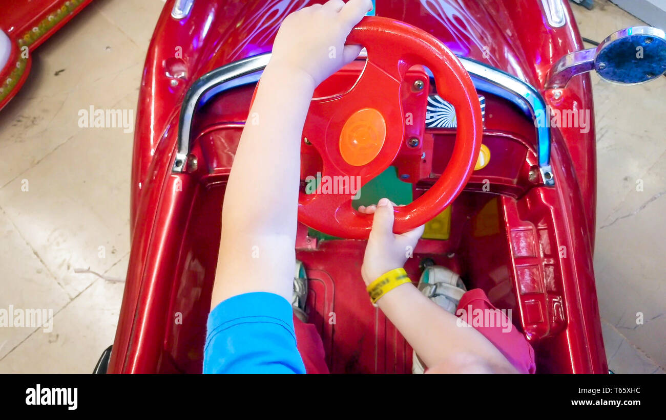 Closeup image of toddler boy playing with insert coin toy car in ...