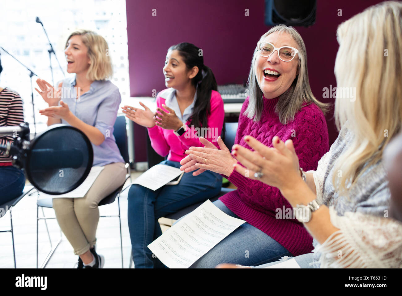 Happy womens choir with sheet music singing in music recording studio ...