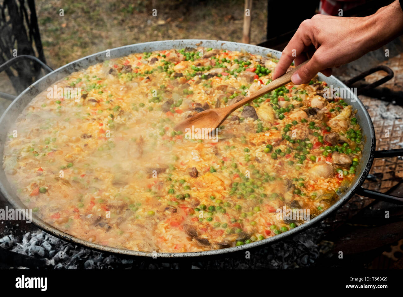 closeup of a young caucasian man preparing a typical spanish paella, in ...