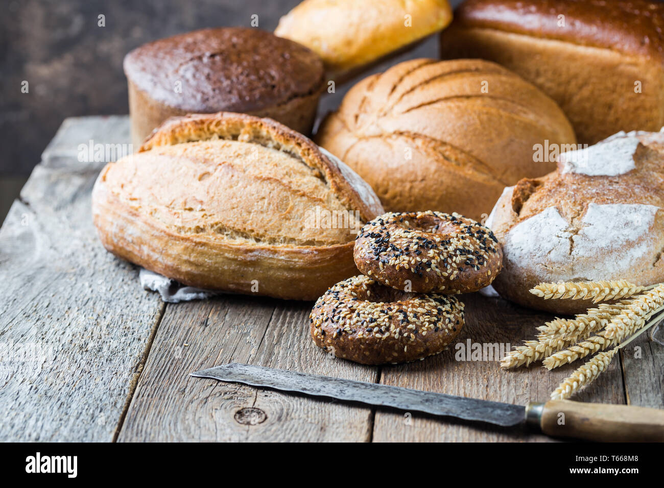 Assortment of fresh baked bread and buns on wooden table background ...