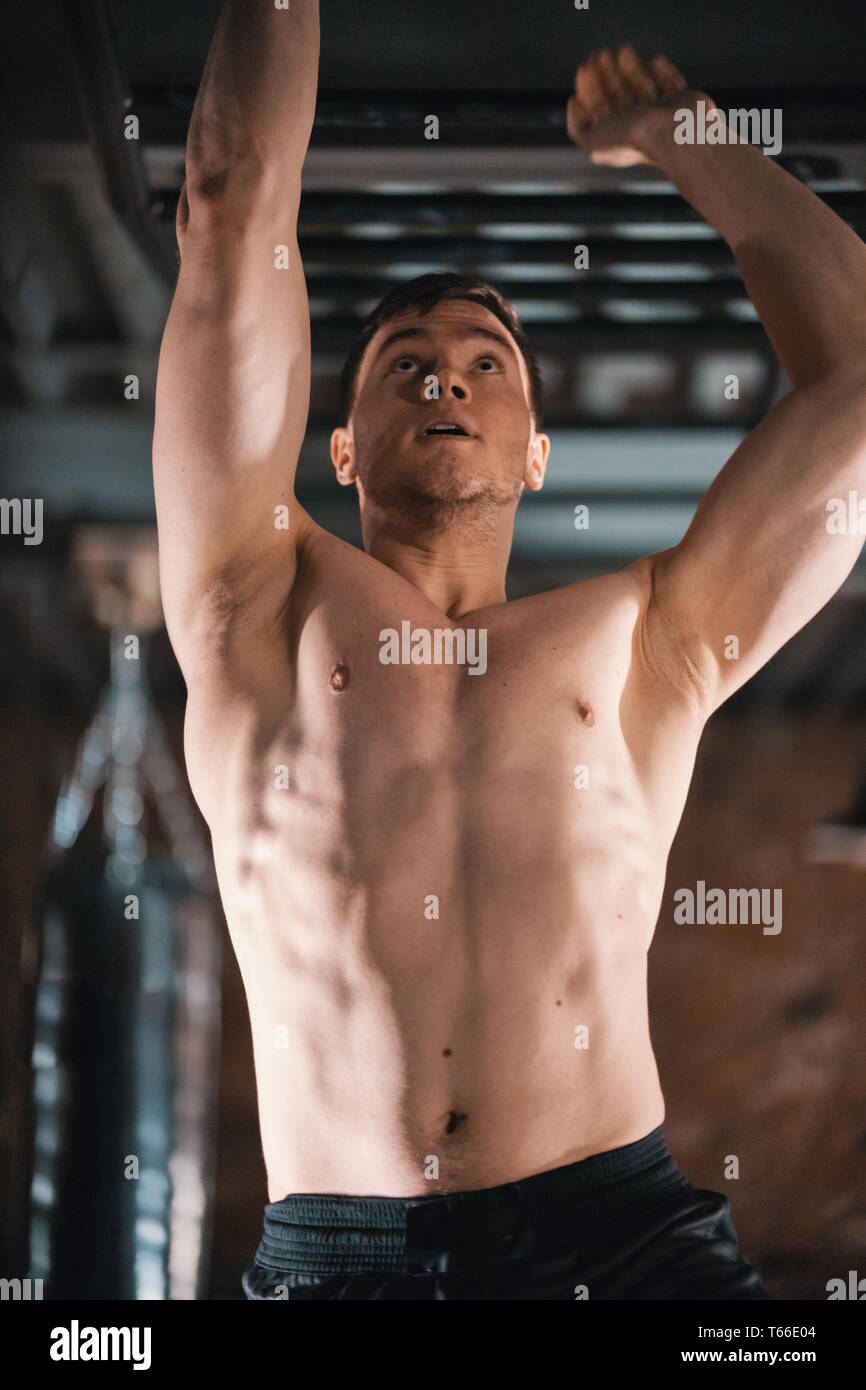 A man in a good shape moving forward on his hands using a ceiling ...