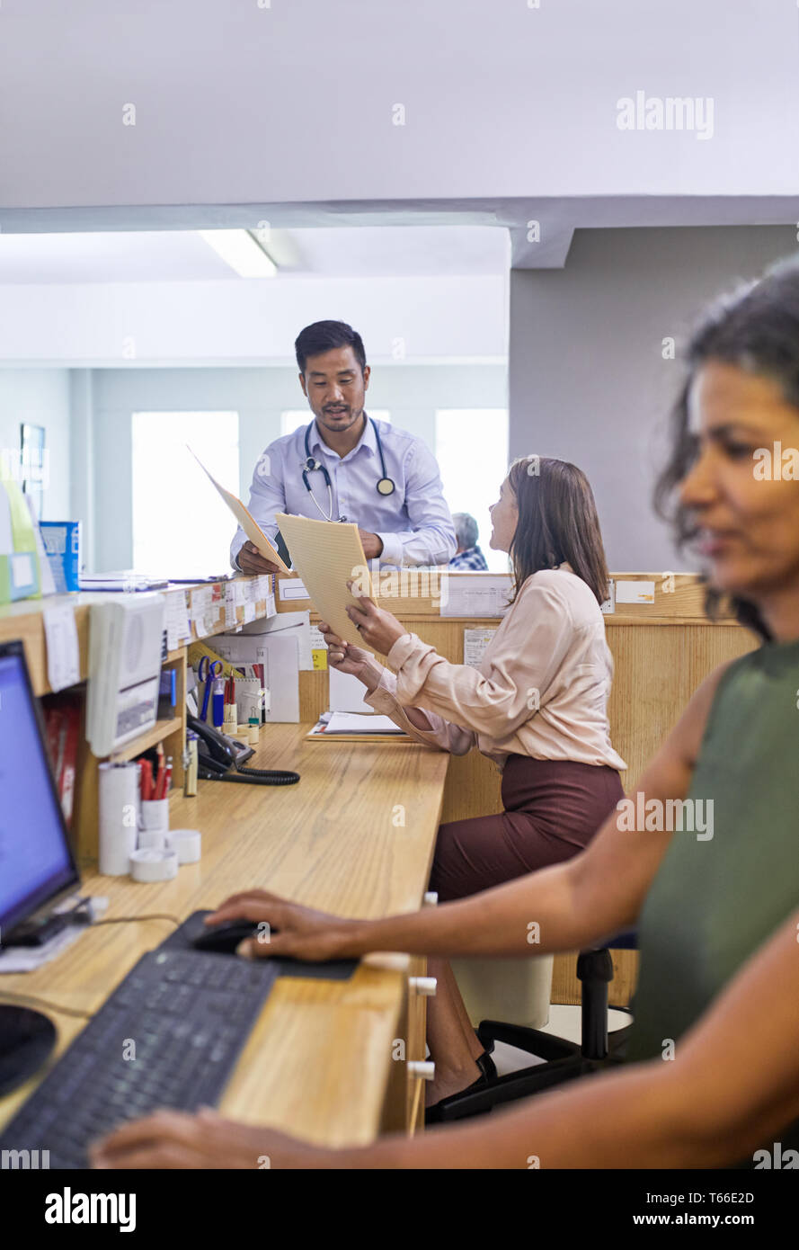 Doctor and receptionist with medical records talking in clinic Stock ...
