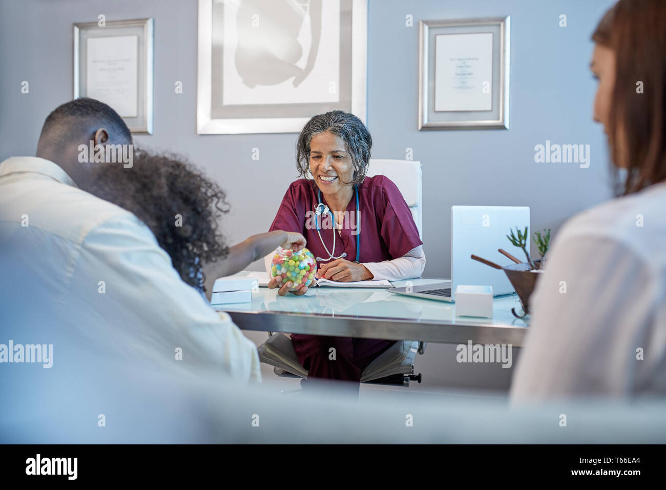 Female doctor giving candy to girl in doctors office Stock Photo - Alamy