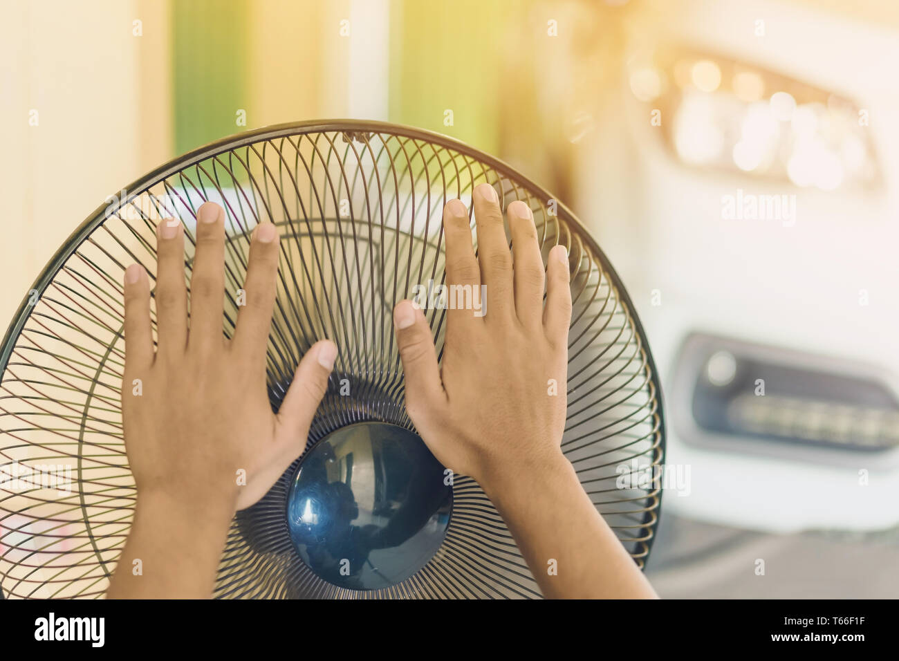 Hand of Young man touch and adjust on front grills of electric fan for ...