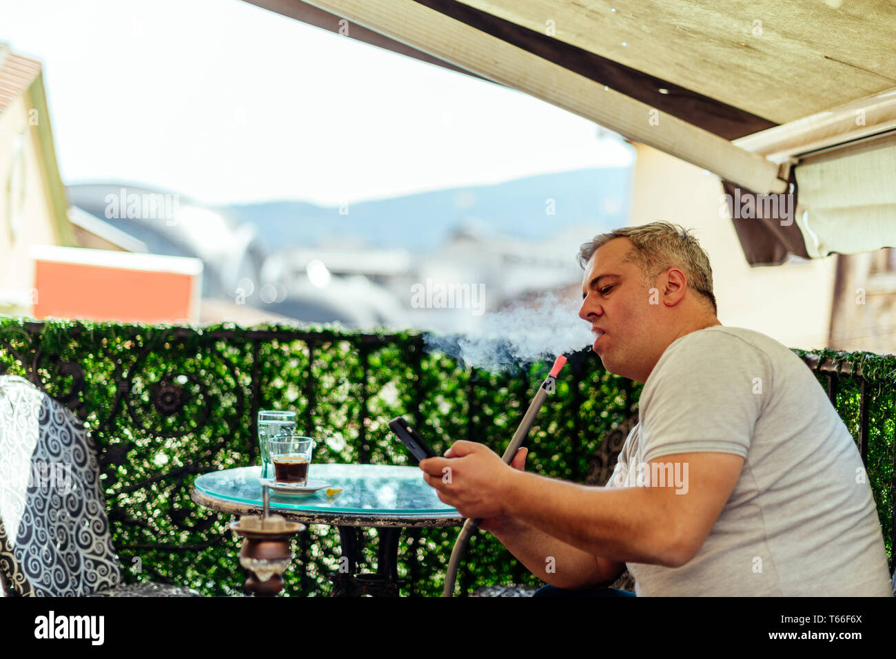 Senior businessman drinking coffee and smoking nargile in nargile bar ...