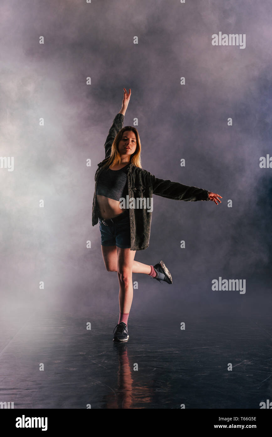 Female dancer shows off her elegance by moving her back leg high over ...