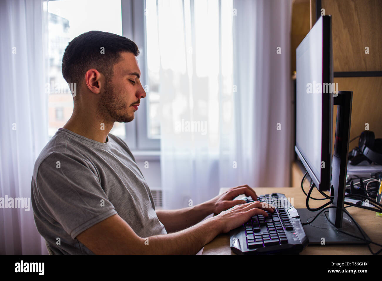 Serious man using desktop pc while typing on keyboard in his room Stock ...