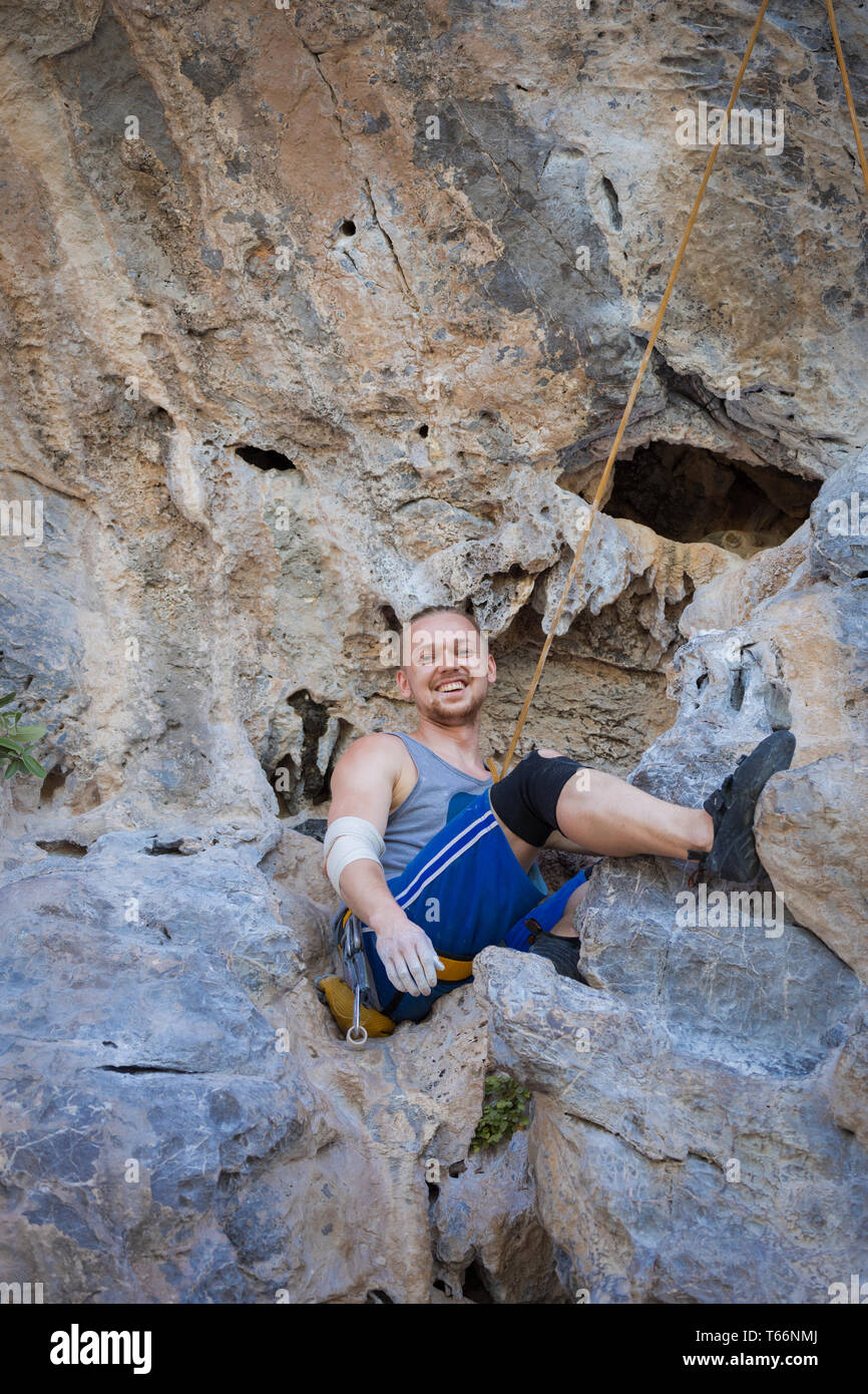 Young man rock climbing on karst limestone white mountain in Thailand ...