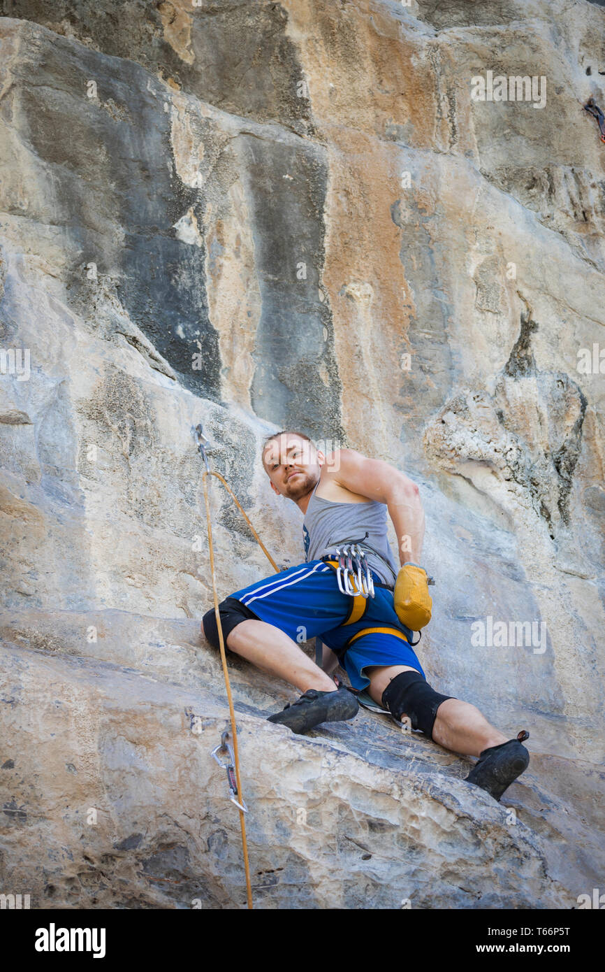 Young man rock climbing on karst limestone white mountain in Thailand ...
