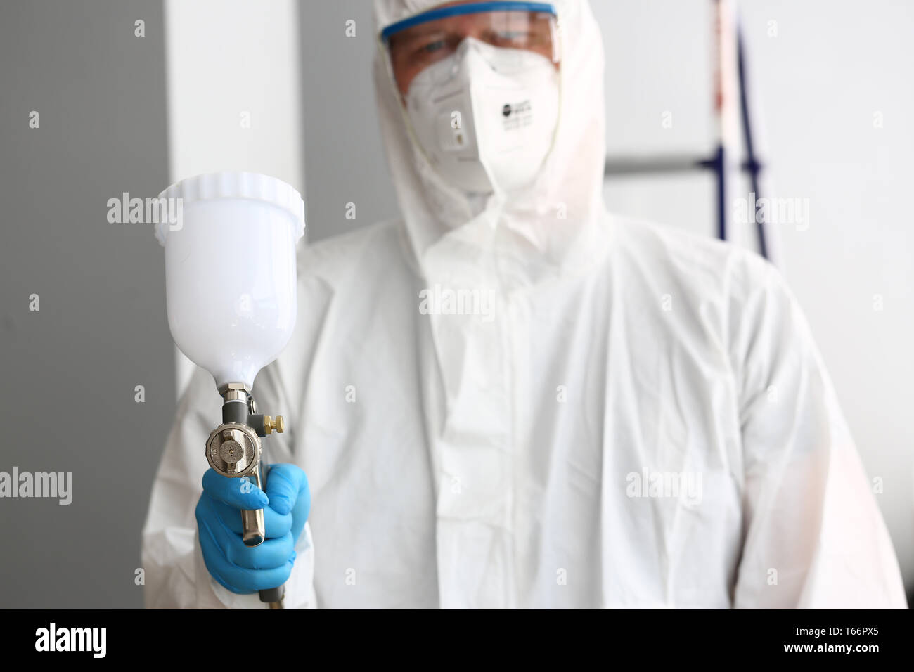 Workman hold in hand sprayer wearing protective suit Stock Photo - Alamy