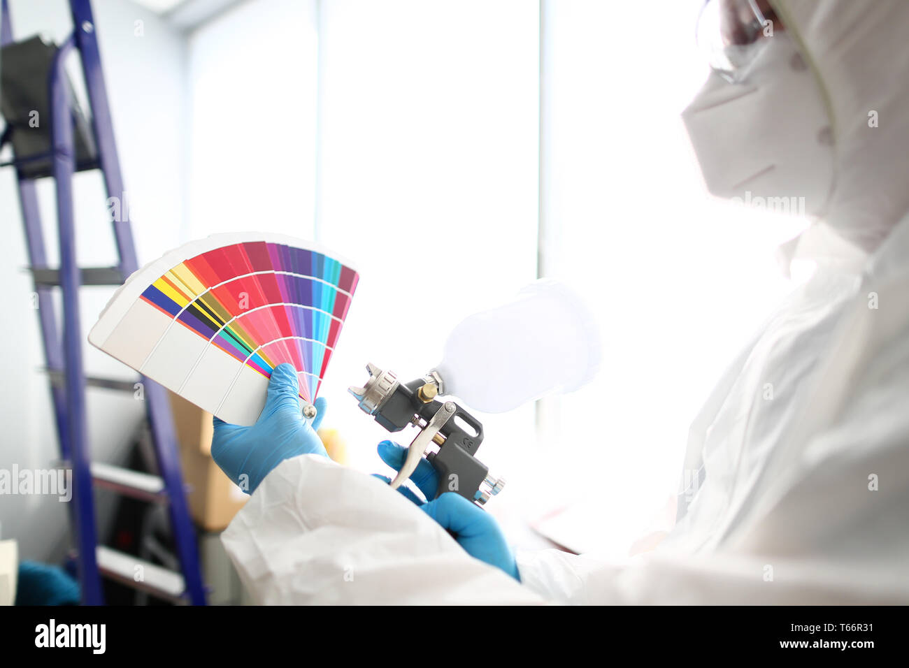 Hands of workman holding airbrush and colorful fantail picking wall ...