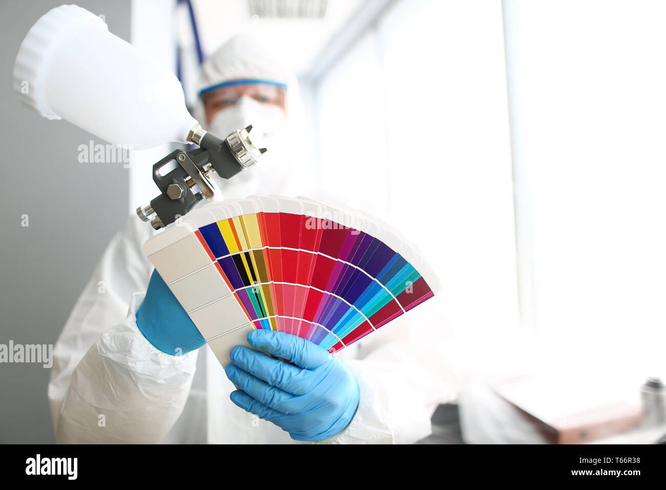 Hands of workman holding airbrush and colorful fantail picking wall ...