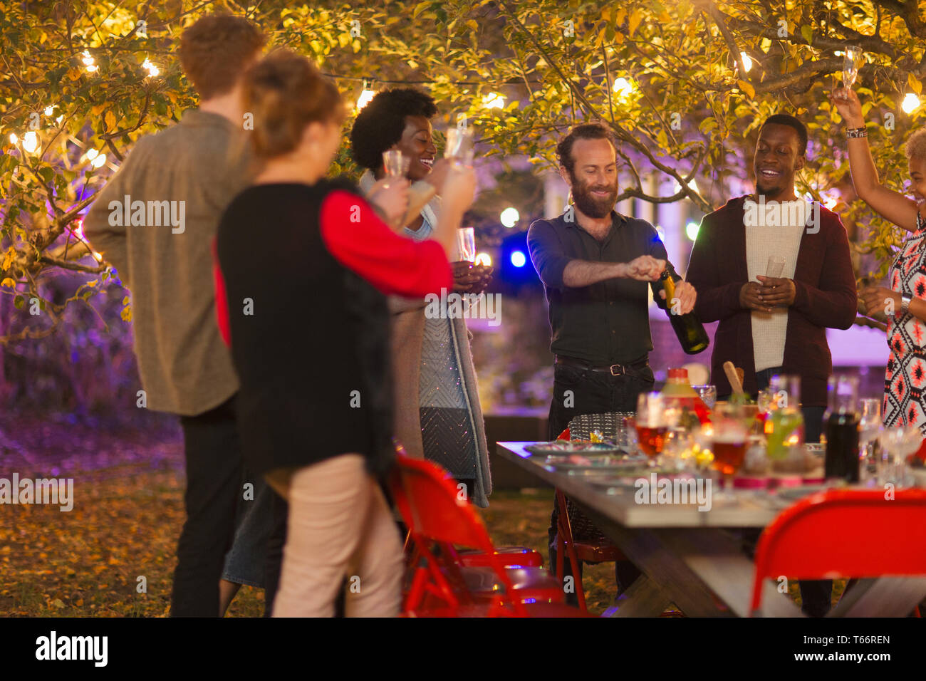 Friends celebrating, opening champagne at dinner garden party Stock ...