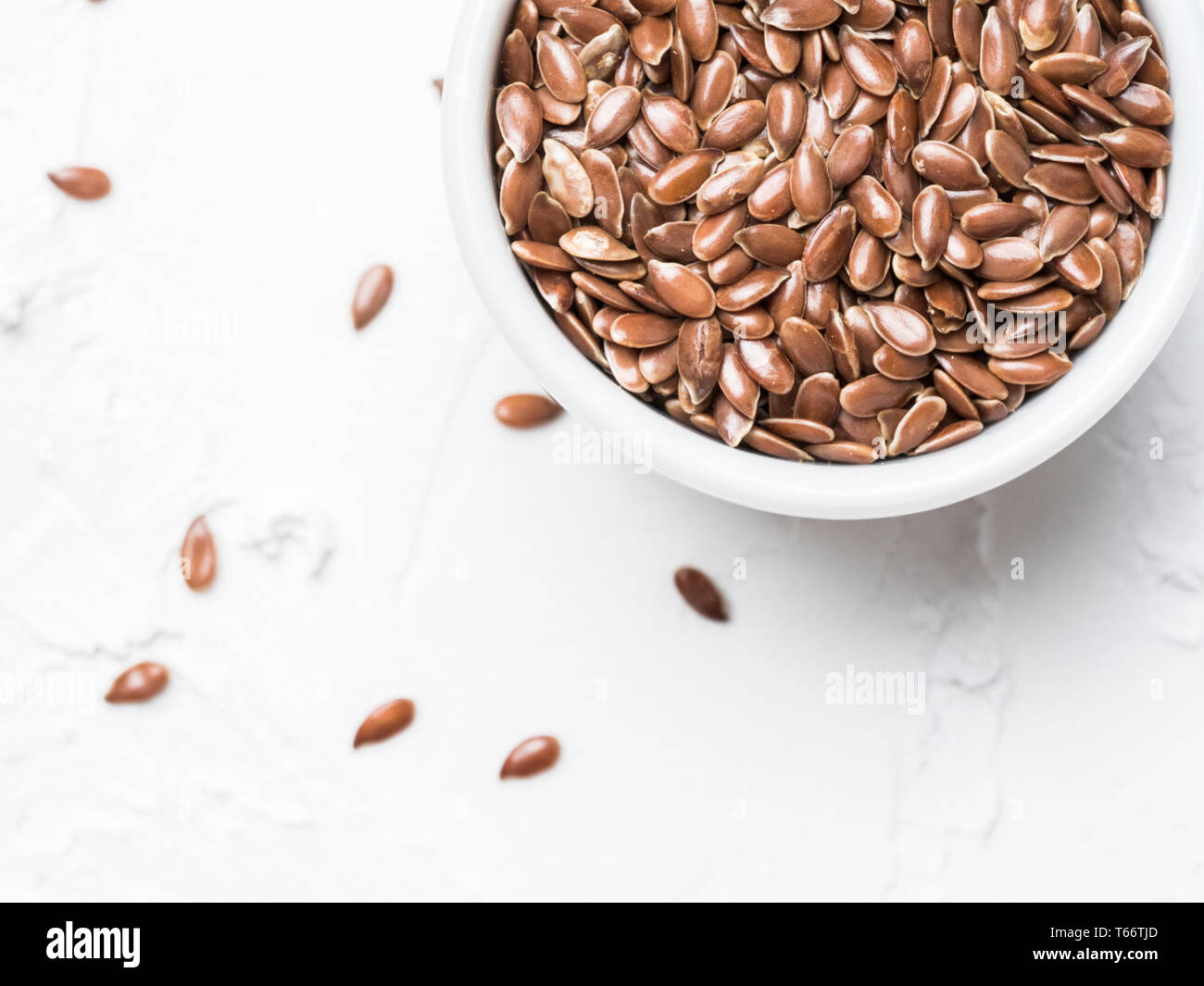 Flax seeds with copy space. Brown flax seed on white concrete textured background. Top view or ...