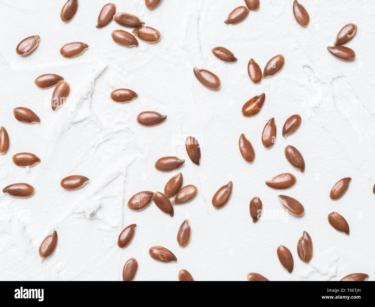 Flax seeds pattern. Brown flax seed on white concrete textured background. Top view or flat lay ...