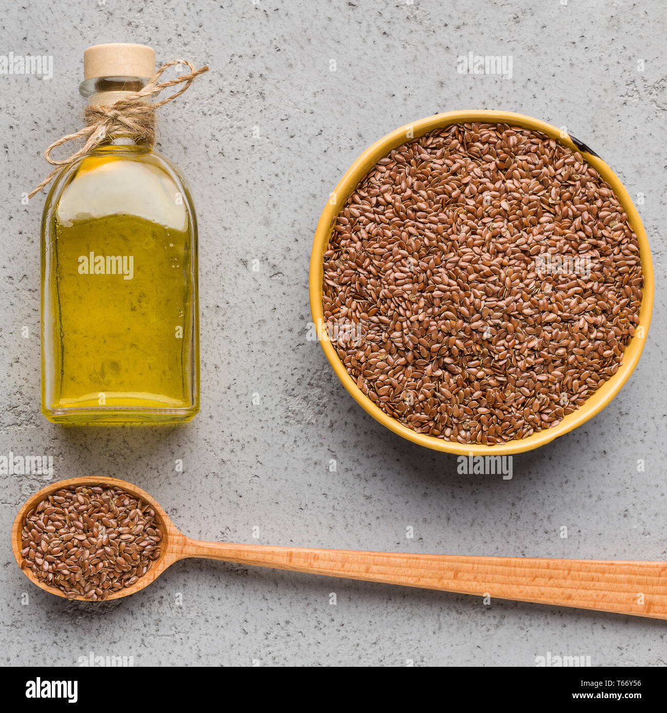 Linseed oil in bottle, bowl and spoon of linseeds on concrete ...
