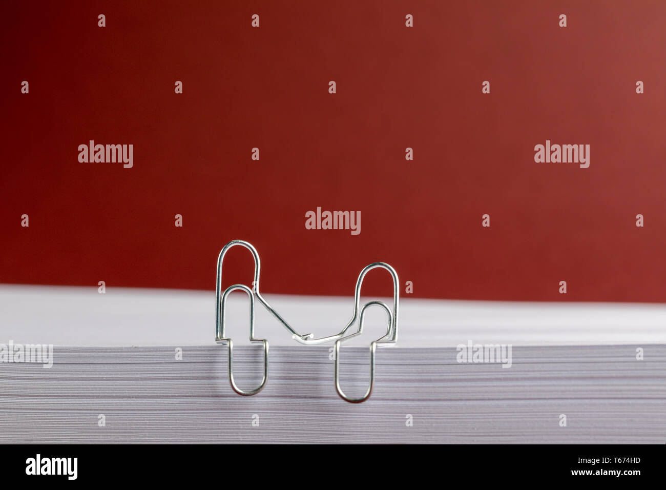 Paper Clips Holding Hands on Paper Pile on Red Background Stock Photo ...
