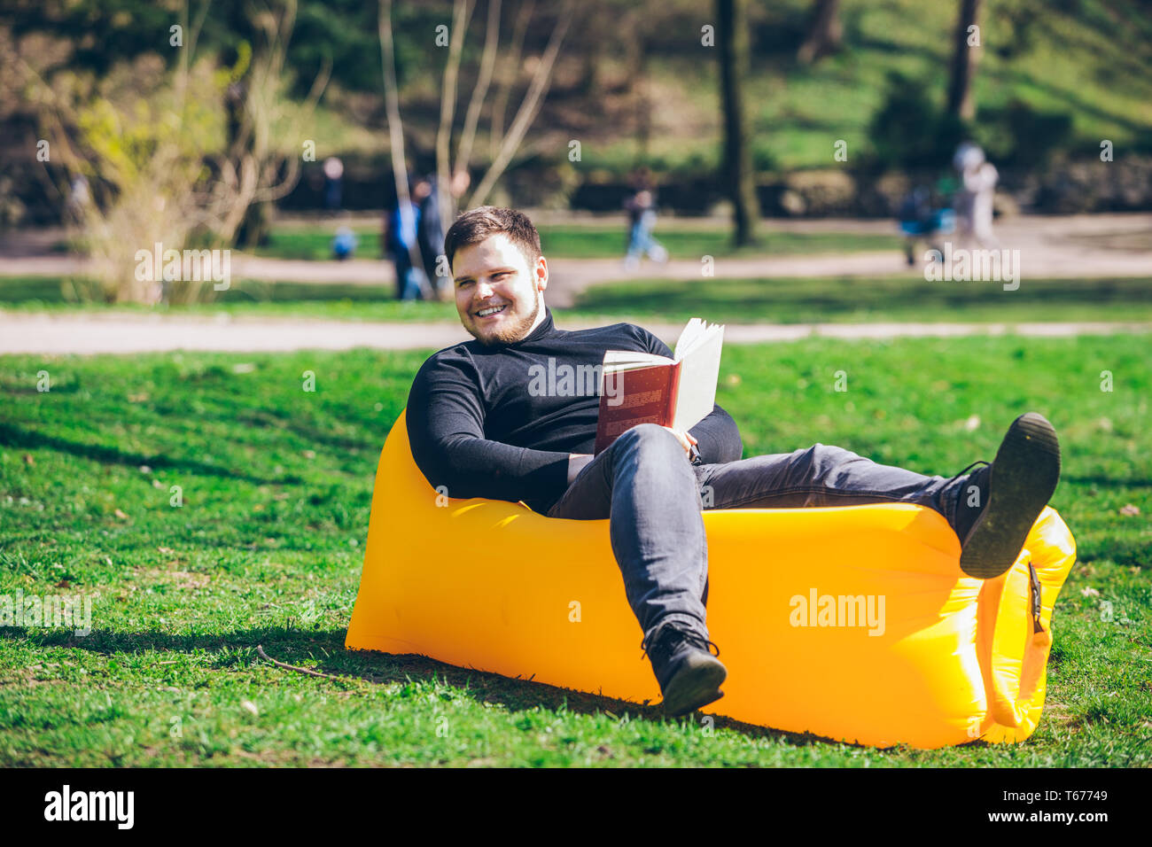 book reading concept. man in city park on inflatable mattress. spring ...
