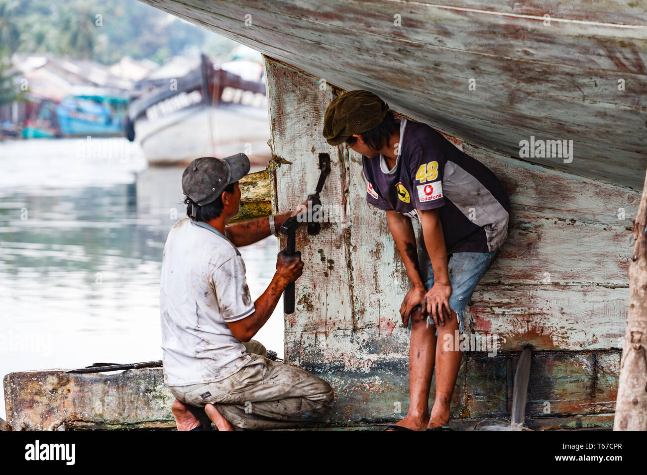 Closeup of men working on the hull of ship scraped ready for painting ...