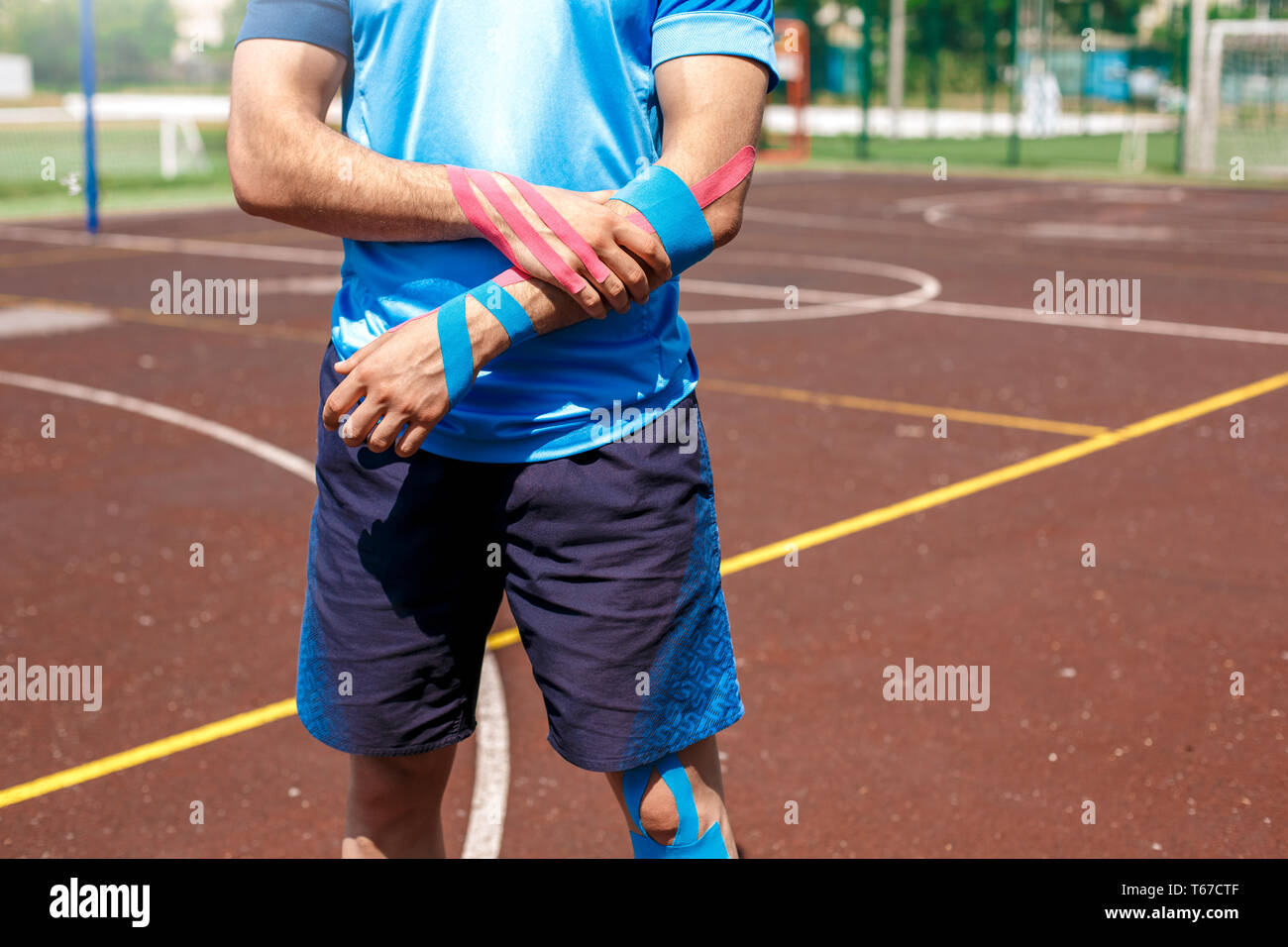Young sportsman on stadium outside standing on track wearing kinesio ...