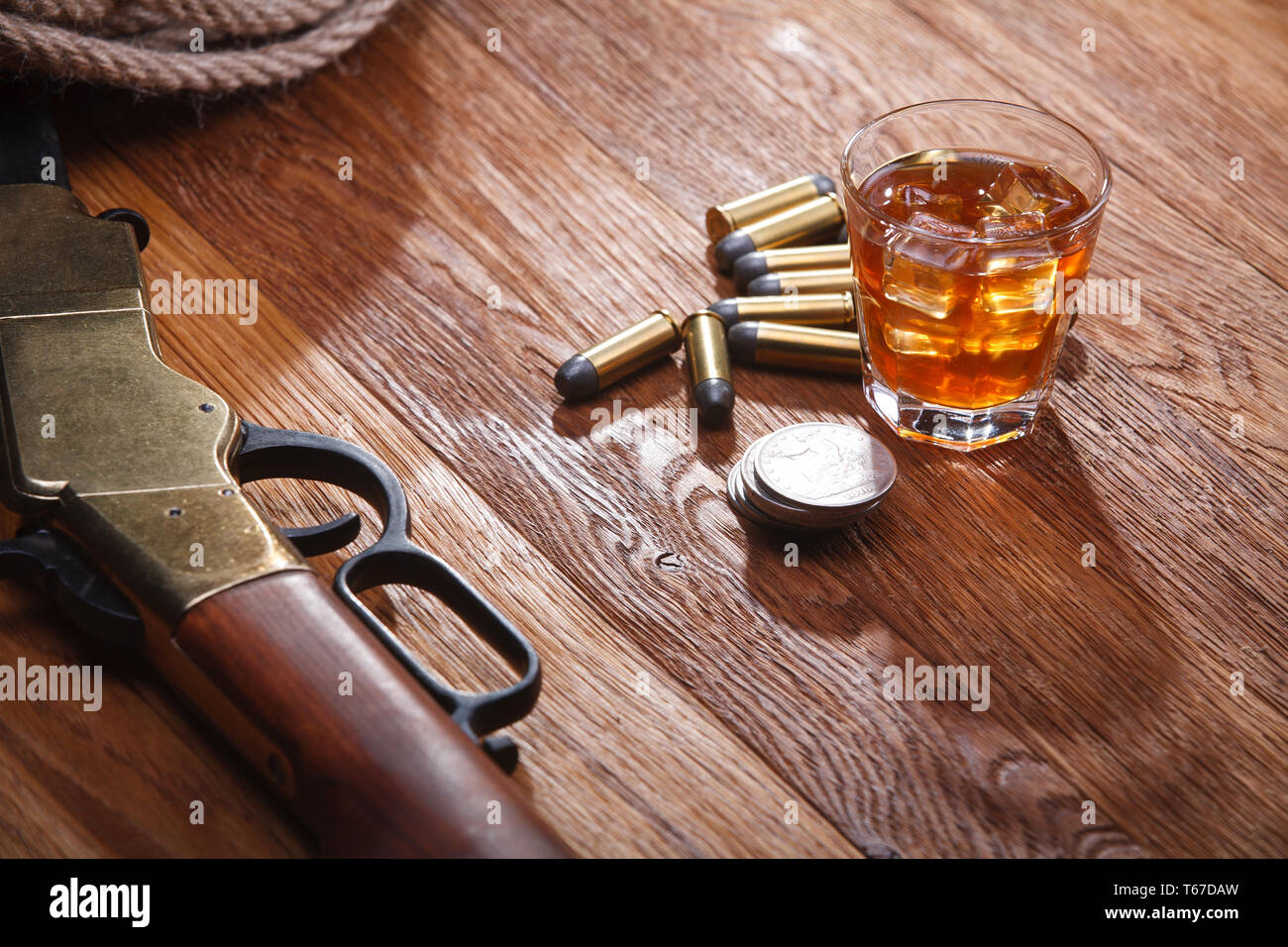 Wild west rifle and ammunitions with glass of whisky and ice with old ...