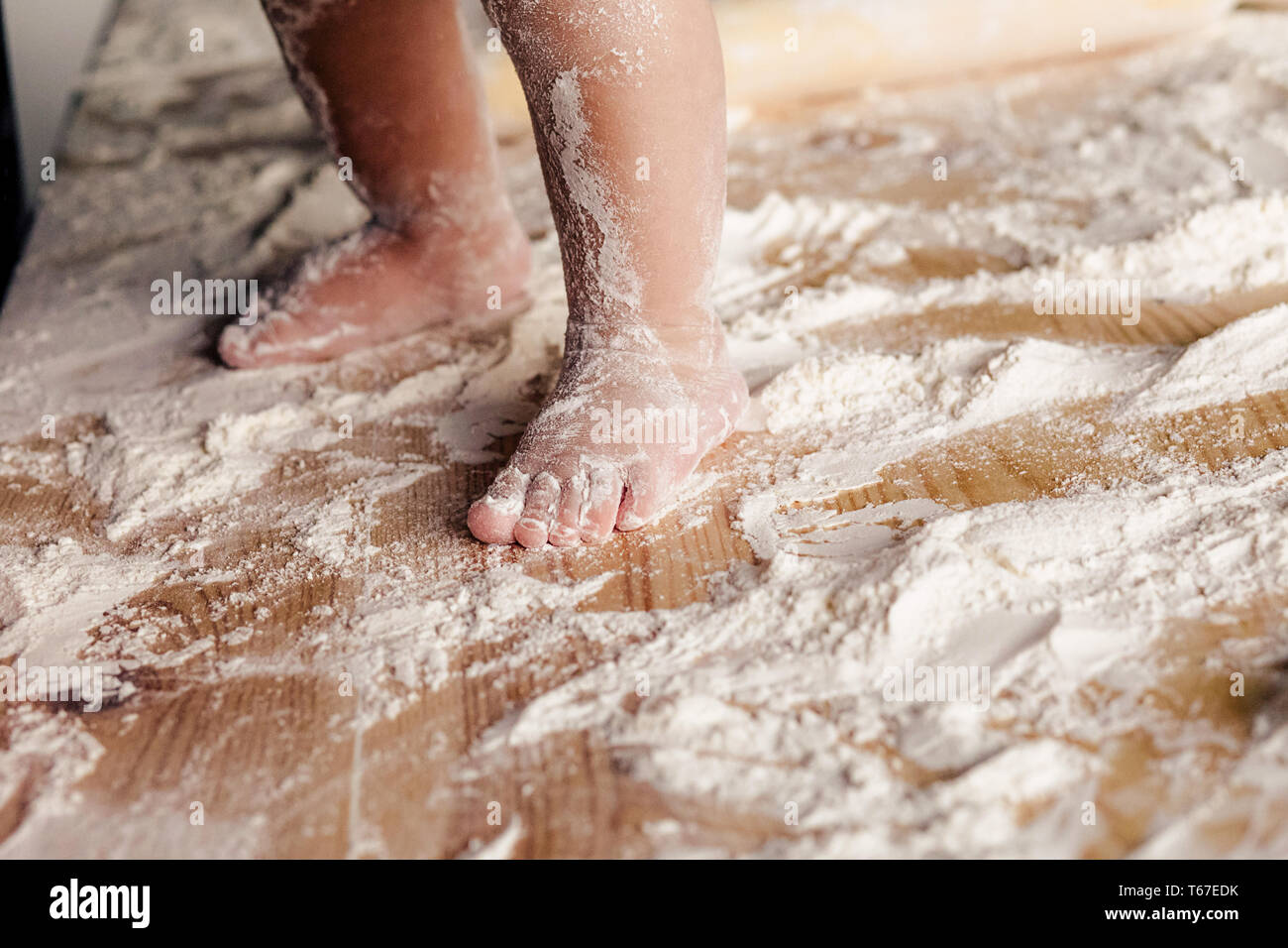 close-up baby's feet in flour. baking preparation stage. little game ...