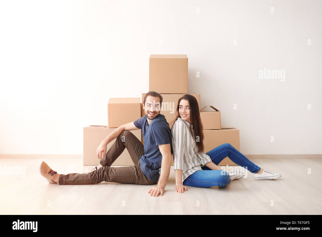 Young couple sitting on floor near cardboard boxes after moving into ...