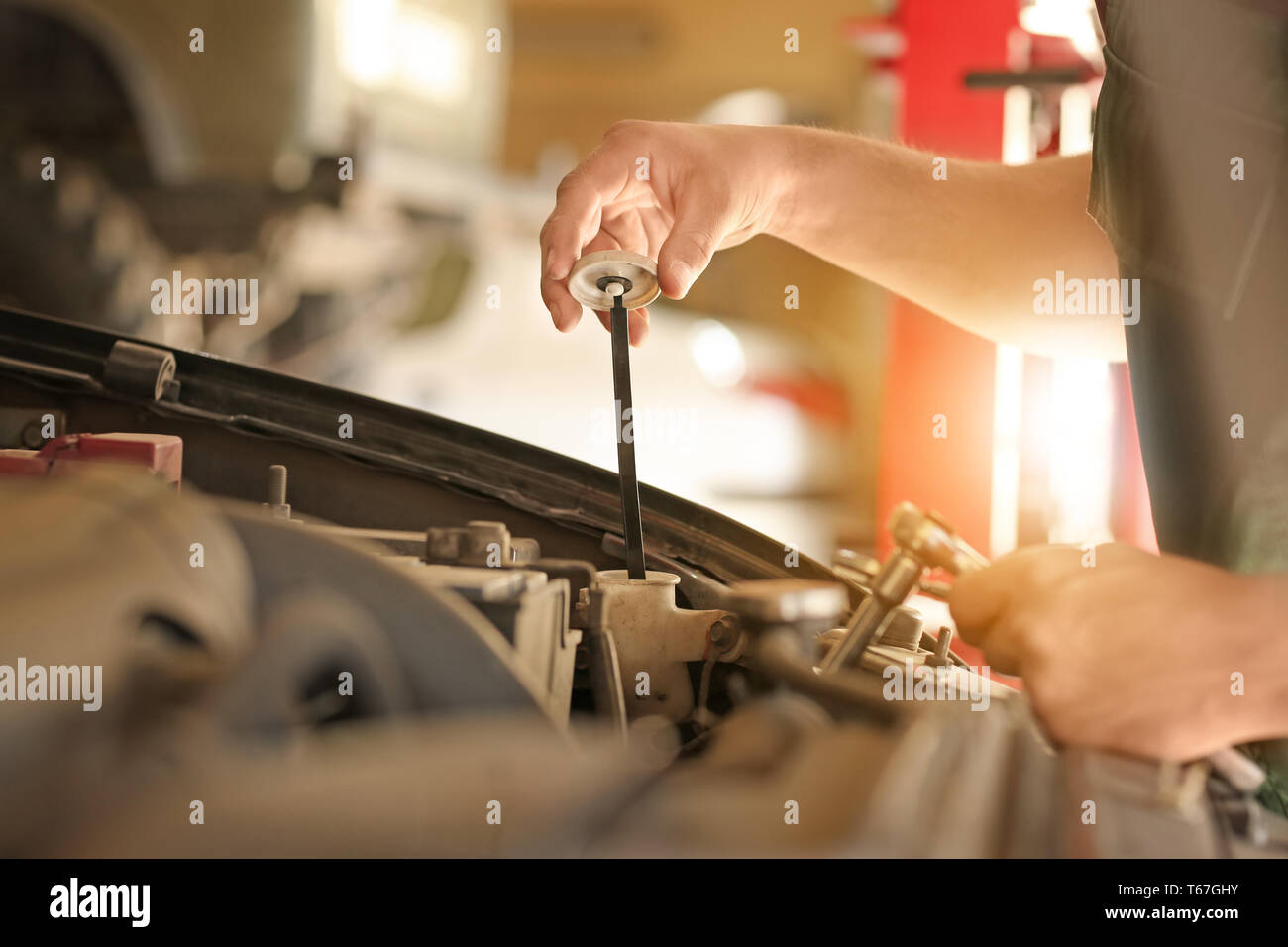 Young mechanic checking engine oil level in car service center Stock ...