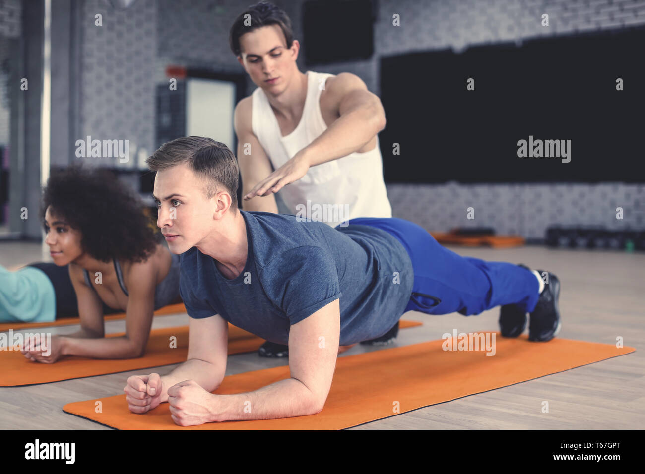 Sporty young people doing exercise in gym Stock Photo - Alamy
