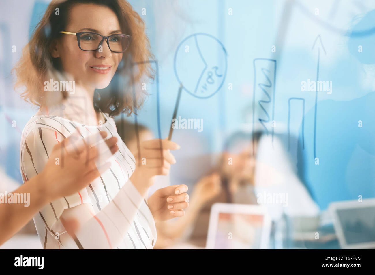 People discussing diagram drawn on transparent board during business ...
