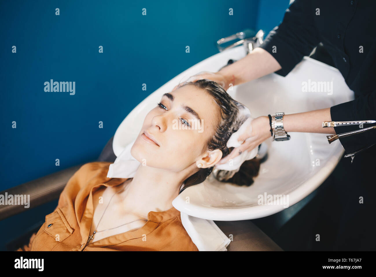 beauty and people concept. Hairdresser washing hair of happy young ...